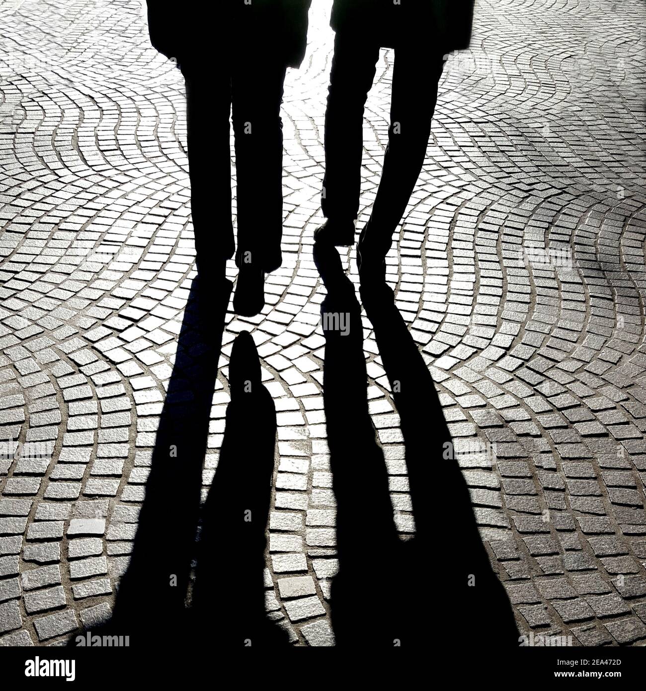 A greyscale shot of the shadows of two people's shadow walking on the ...