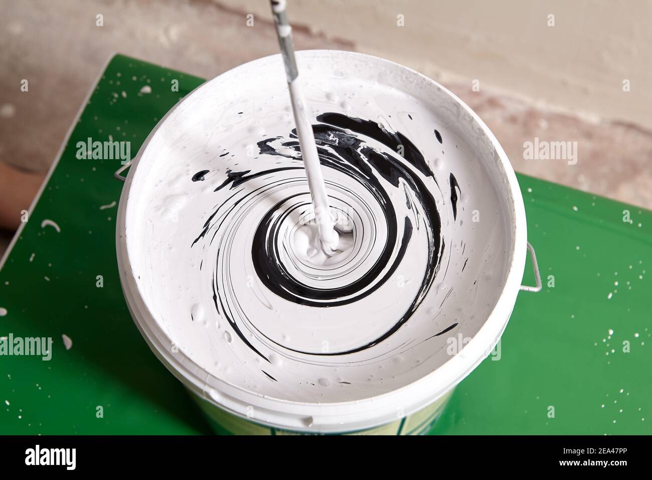 House painter mixes two paints using mixer for bucket with paddle ...