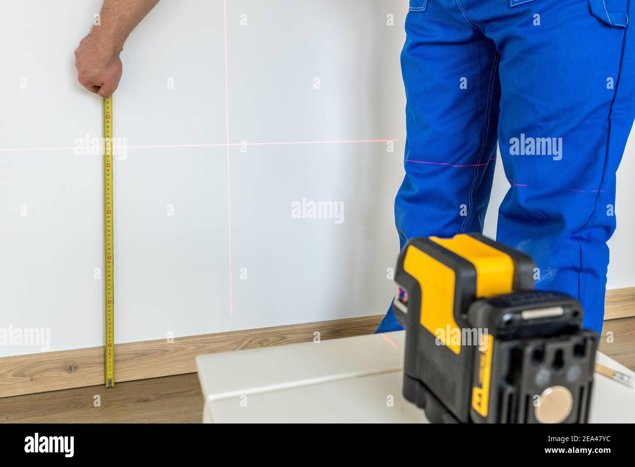 A specialist makes measurements on the wall with a measuring stick and ...