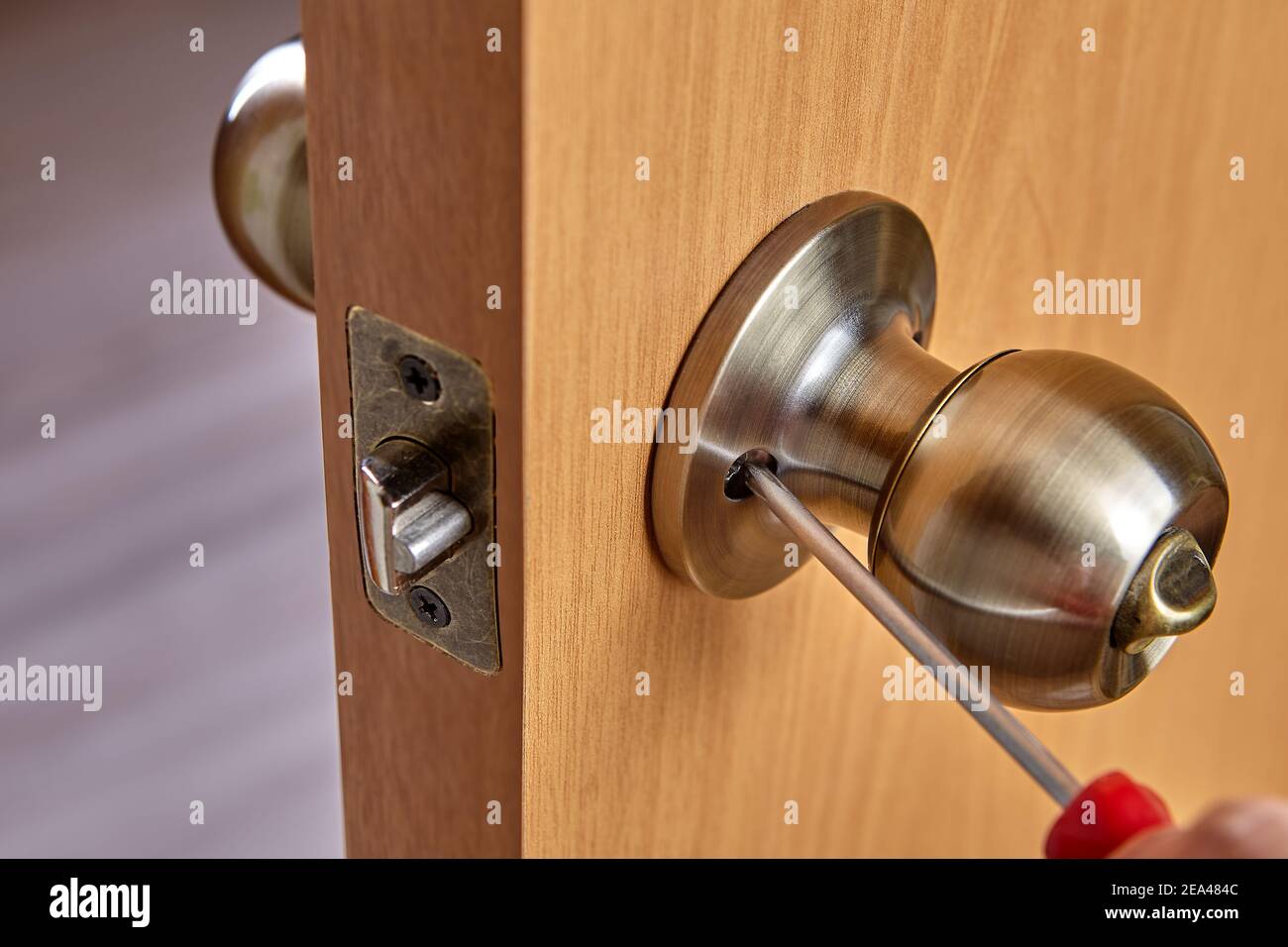 Locksmith fixes door handle rose with screw, using screwdriver Stock ...