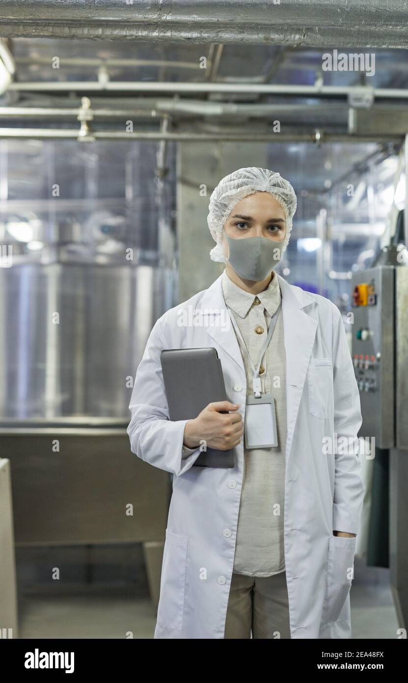Vertical portrait of female worker wearing mask and holding clipboard ...