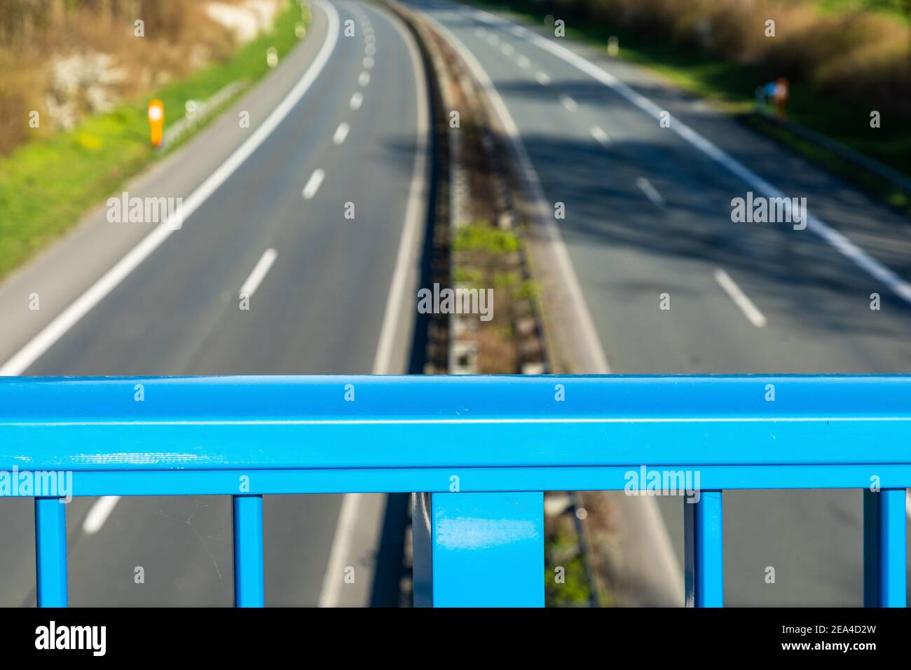 A closeup view of the blue railing of the bridge nad the road on a ...