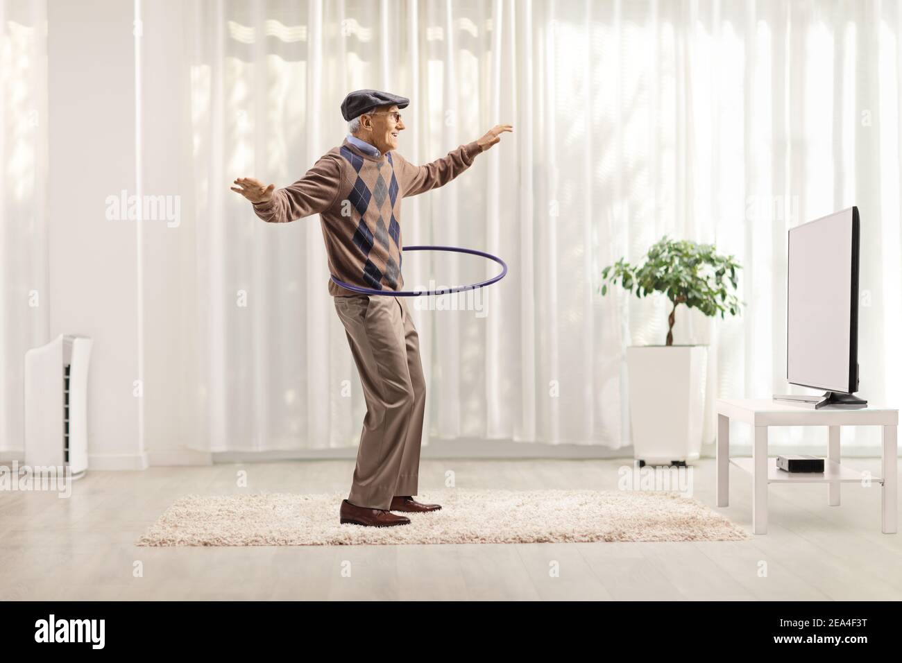 Cheerful man having fun and spinning a hula hoop isolated on white ...