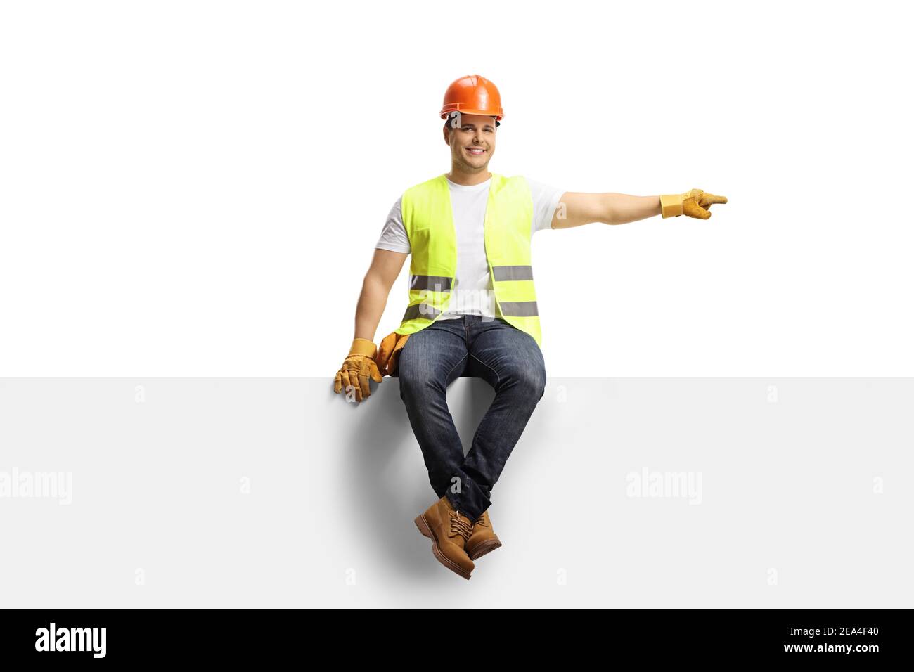 Construction worker with a helmet sitting on a blank panel and pointing ...