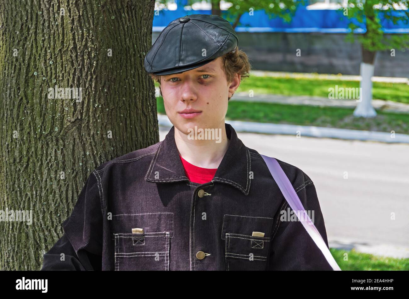 Sulky young bully with black jacket and leather black cap with bruise ...
