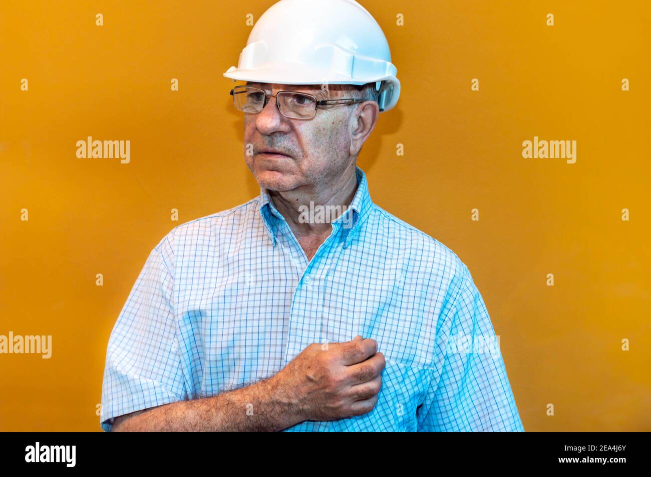 A closeup of a serious Caucasian engineer wearing a safety helmet with ...