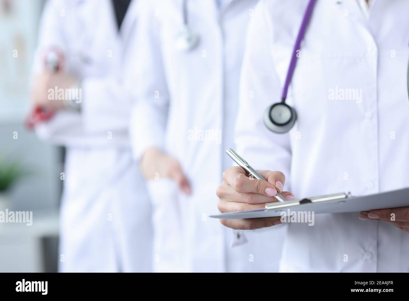 Three doctors stand behind each other closeup Stock Photo - Alamy