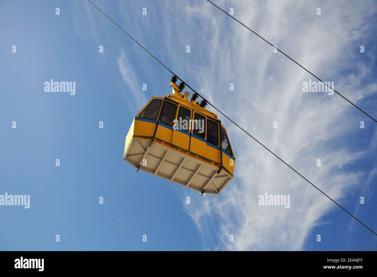 A low angle shot of a yellow cable car cabin under a cloudy sky Stock ...