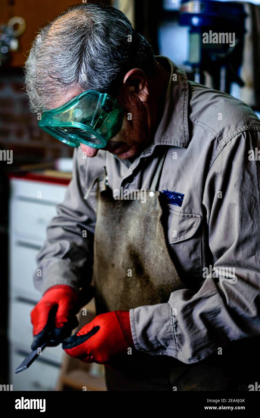 A vertical closeup of a Caucasian engineer wearing safety goggles while ...