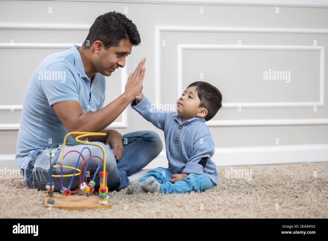 Mexican father and son playing on the carpet at home Stock Photo - Alamy