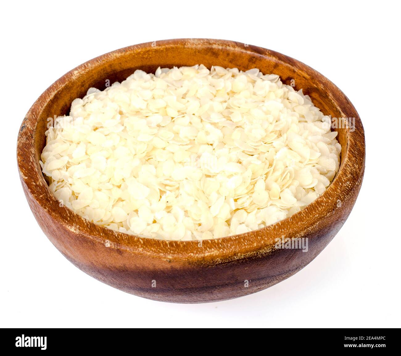 Wooden bowl of flattened rice flakes isolated on white background ...