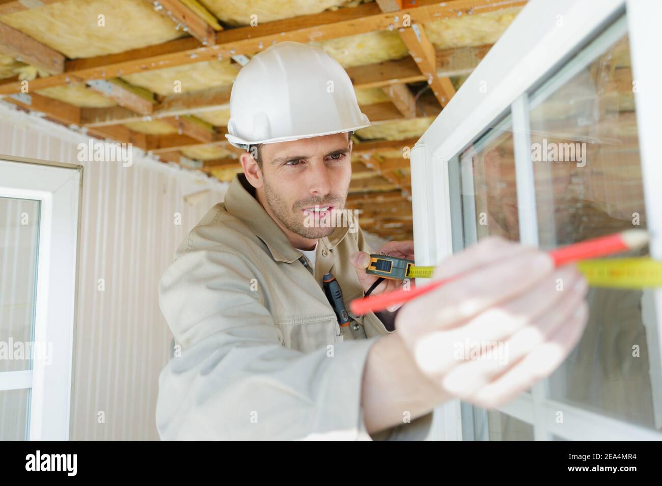 confident young builder measuring window Stock Photo - Alamy