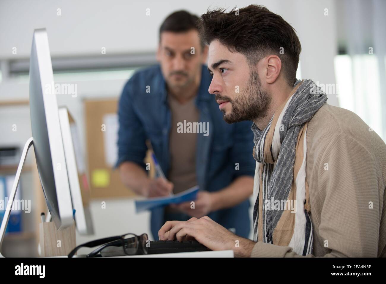 supervisor watching young man using computer Stock Photo - Alamy