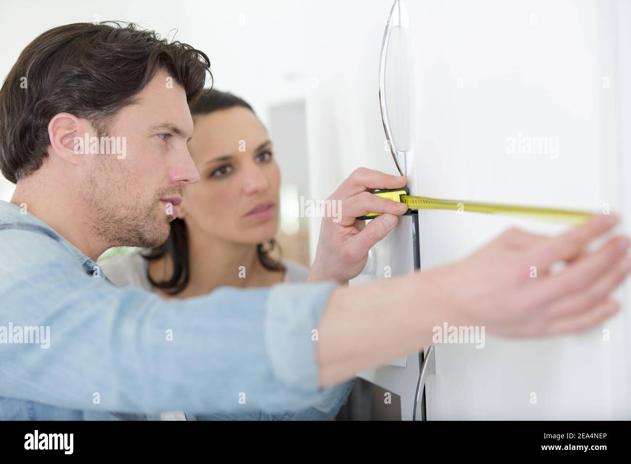 couple in empty apartment measuring walls Stock Photo - Alamy