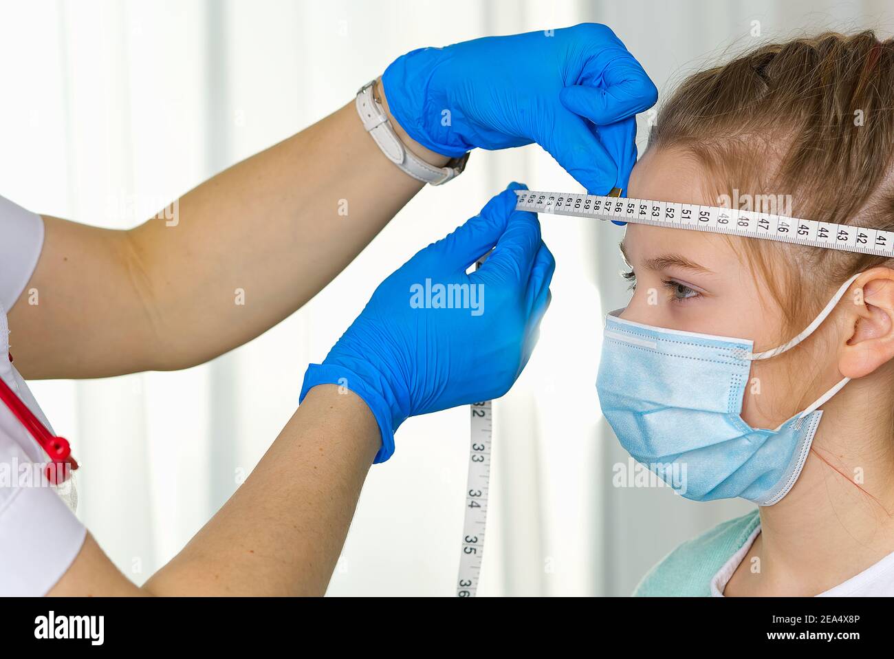 Female doctor measuring patient head in clinic Stock Photo - Alamy