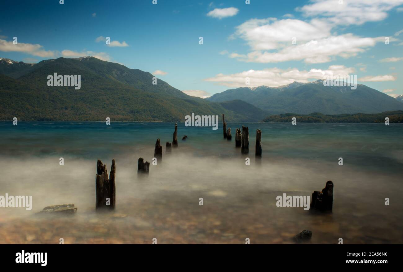 Wooden columns in the sea with mountains in the background Stock Photo ...