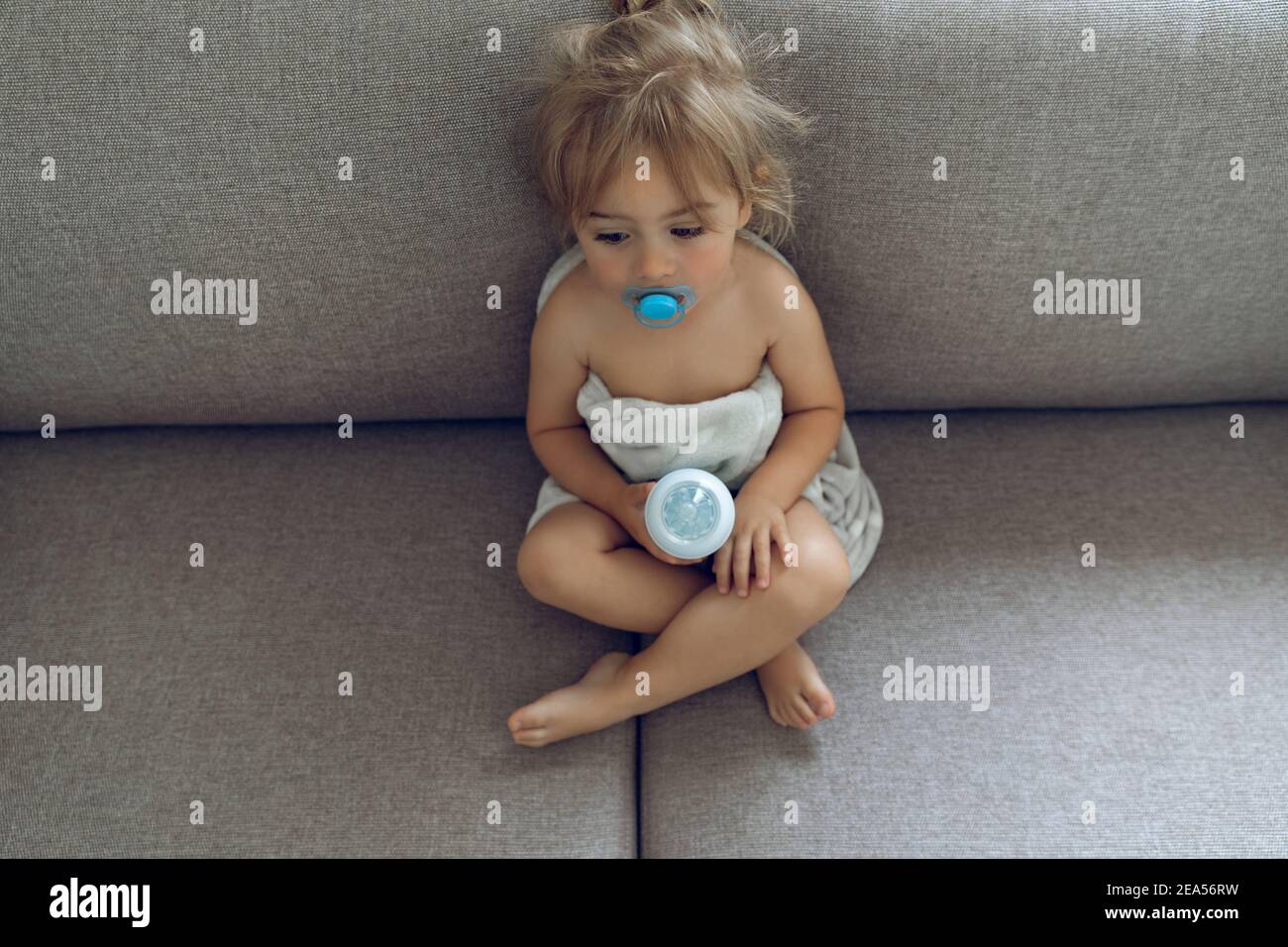 Sweet Adorable Child With Pacifier in the Mouth Sitting on the Sofa at ...
