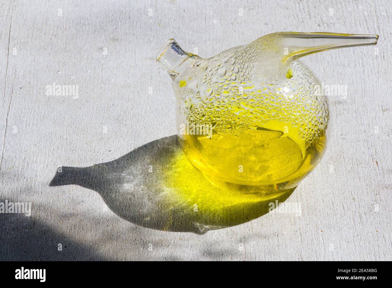 A closeup of a laboratory flask with yellow reagent and shadow on an ...