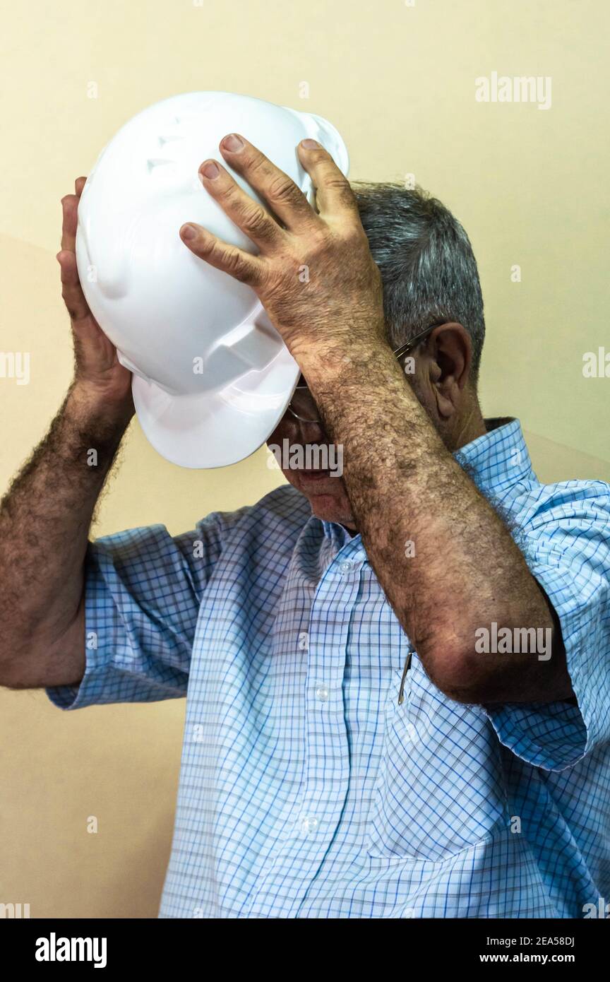 A vertical shot of a Caucasian engineer putting on his safety helmet ...