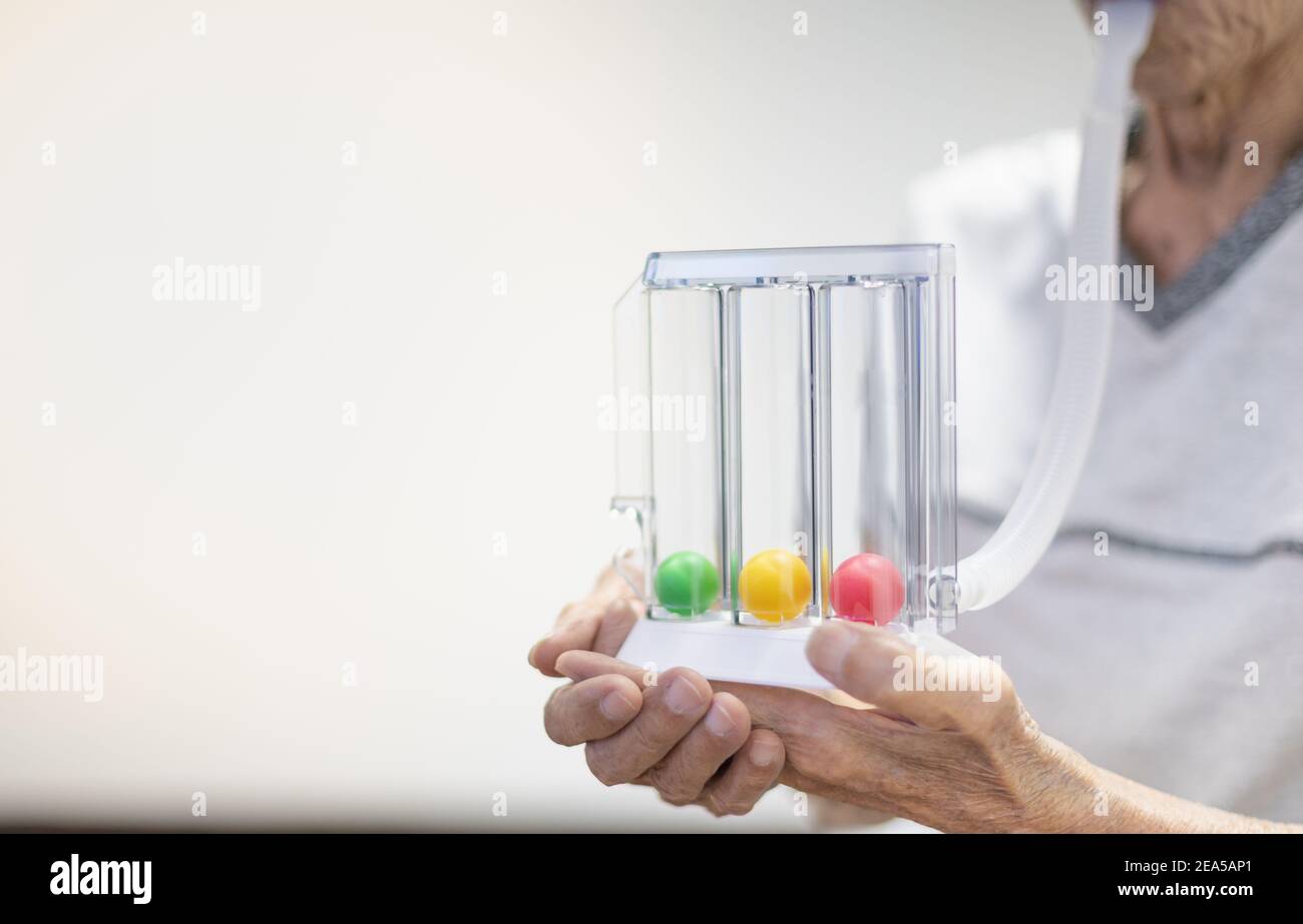 The old patient hand holding the Tri-ball incentive spirometry is ...