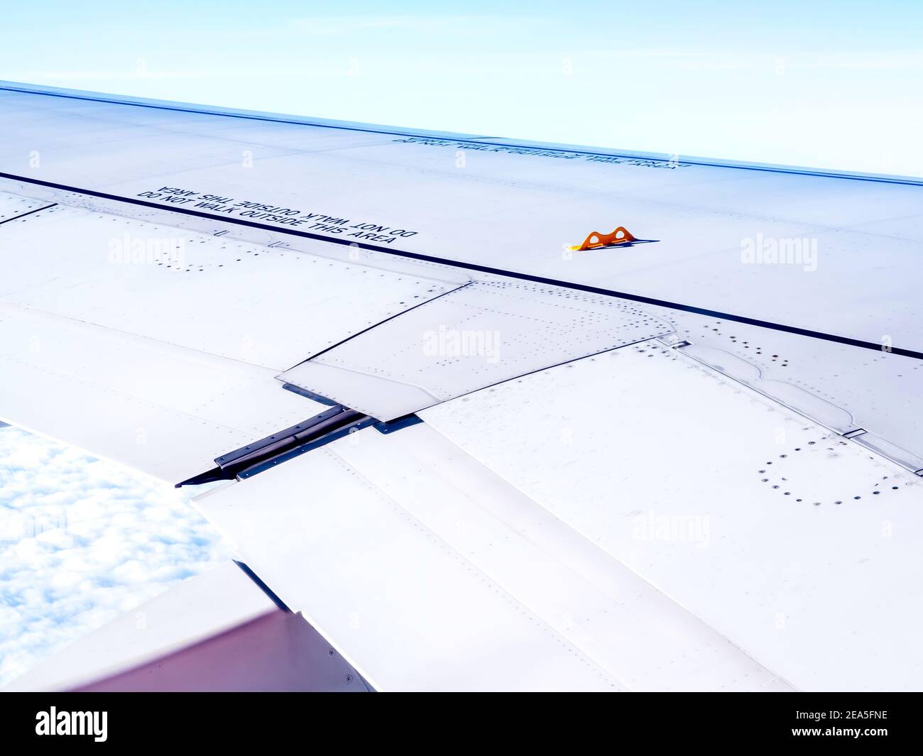 Yellow little hook on airplane wing, view from the window while flying ...