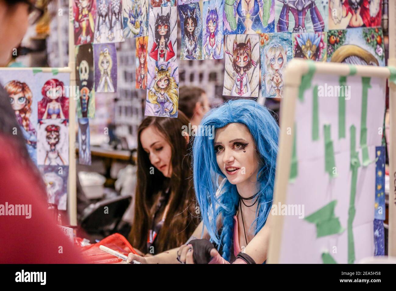 A vendor with blue hair waits for customers at her booth, selling ...