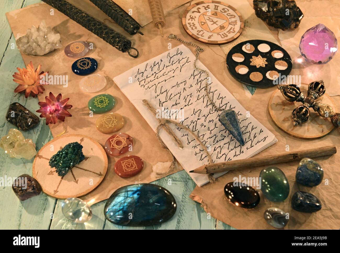 Crystal stones with chakras, candles, ritual objects and paper with ...