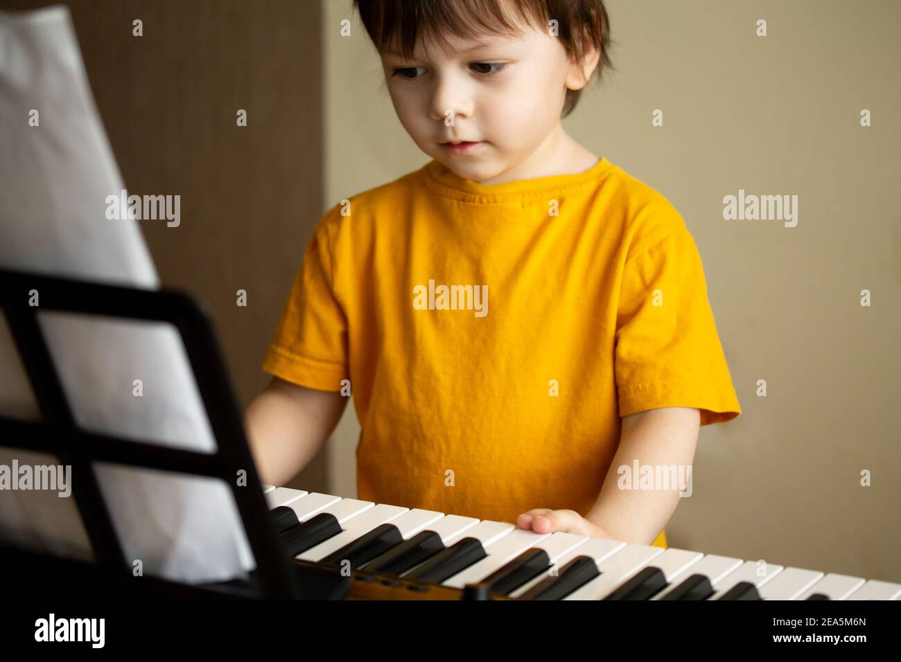 A boy playing the synthesizer. Toddler learning how to play piano ...