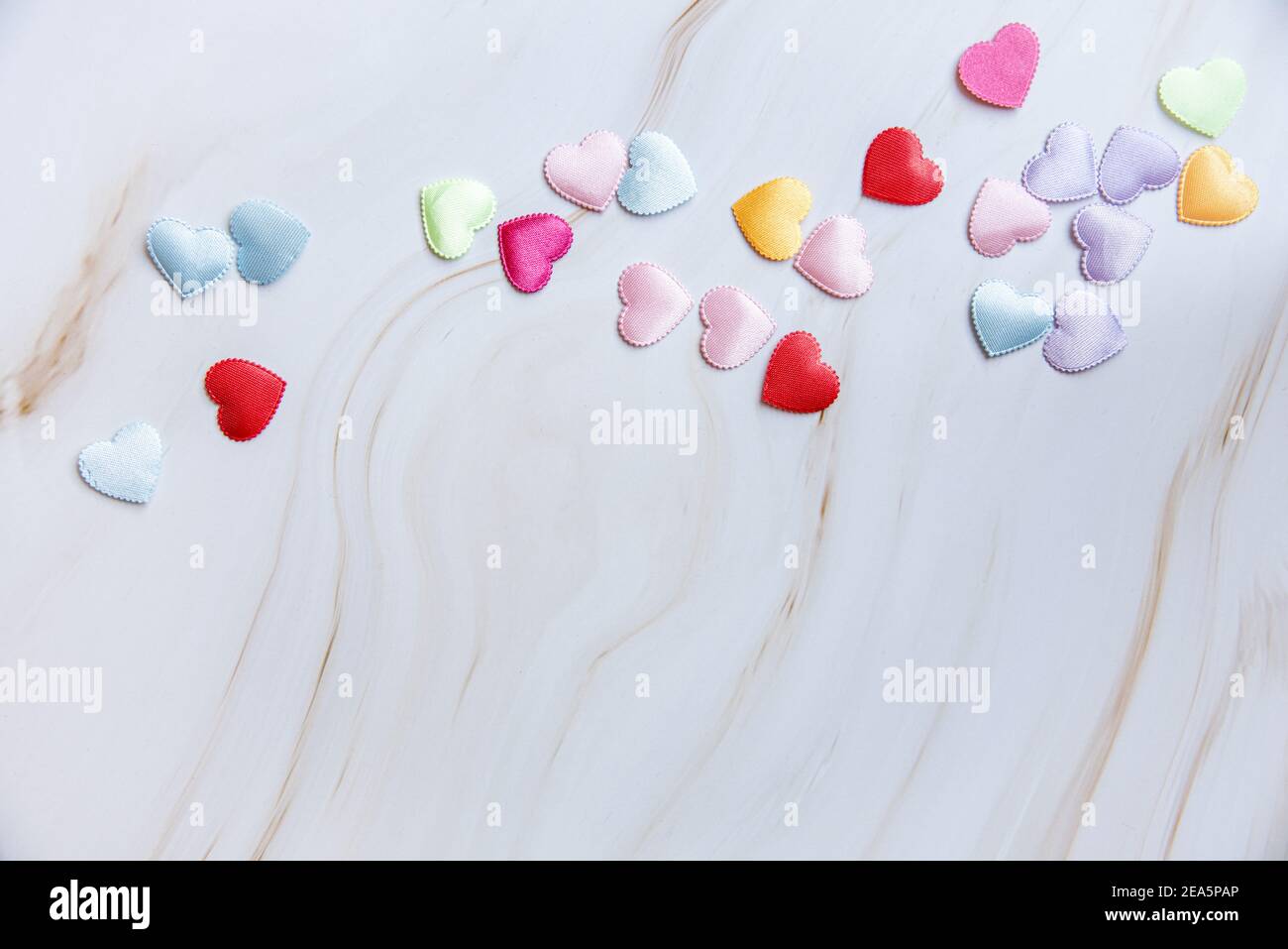 Small colorful heart shapes on a white marble background. Tiny gold ...