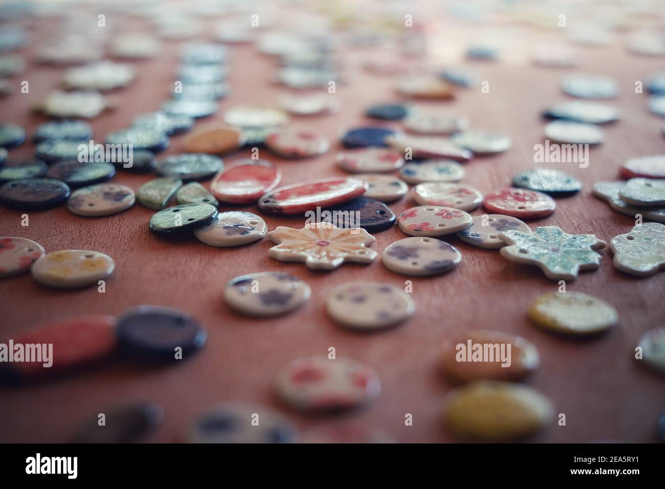 Tiny colorful ceramic buttons being cooled on a table after baking in ...
