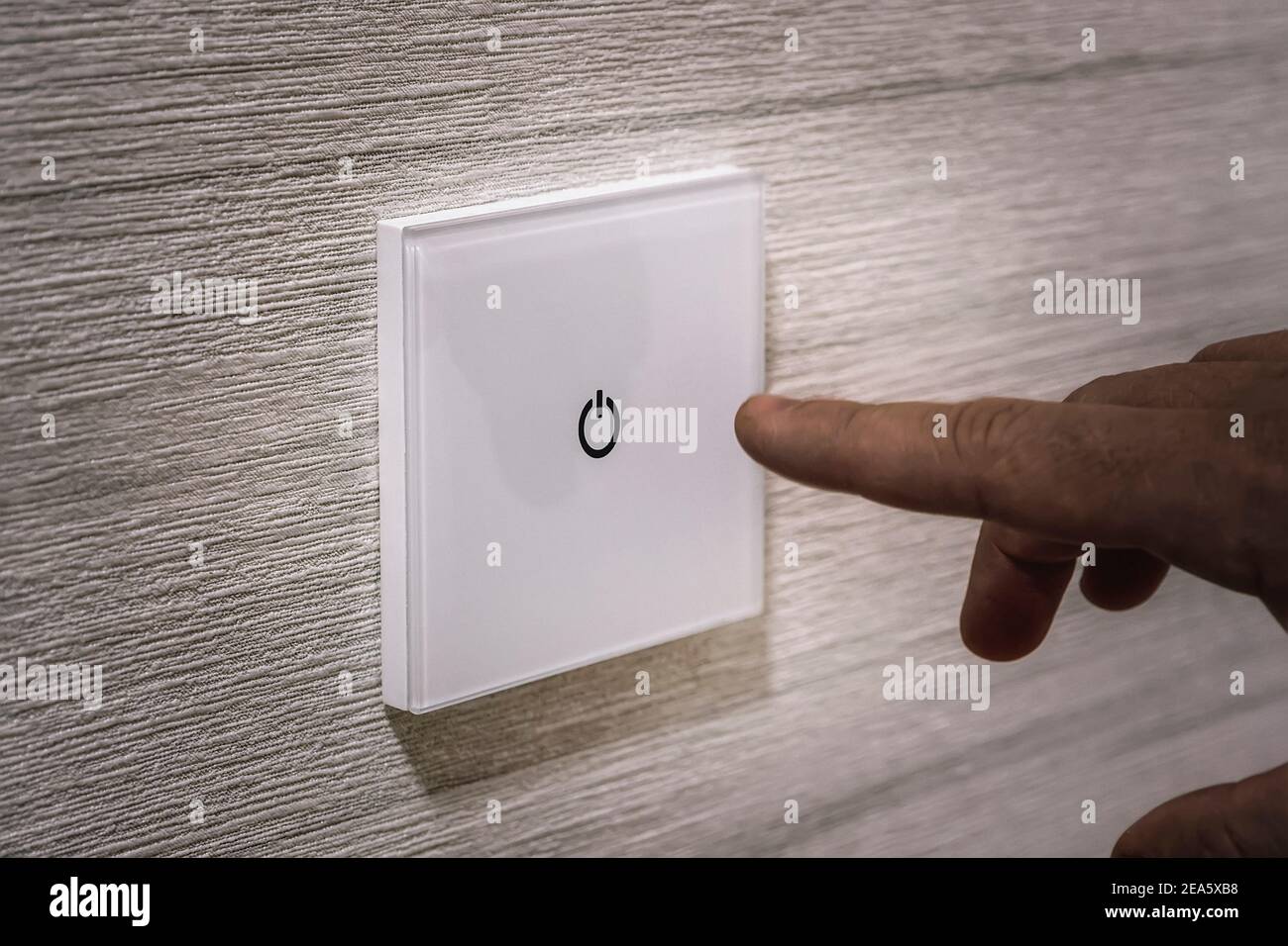 A close-up finger turns on the light on the touch switch. A white ...