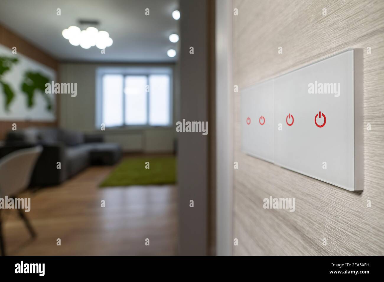 A white modern light switch on a white wall on the background of the ...