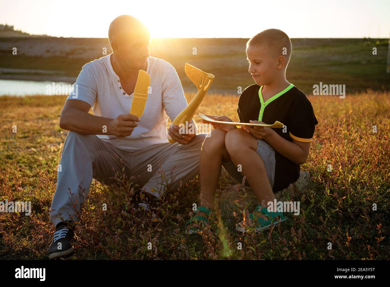 dad and son at sunset in the summer play an airplane in the sun. Family ...