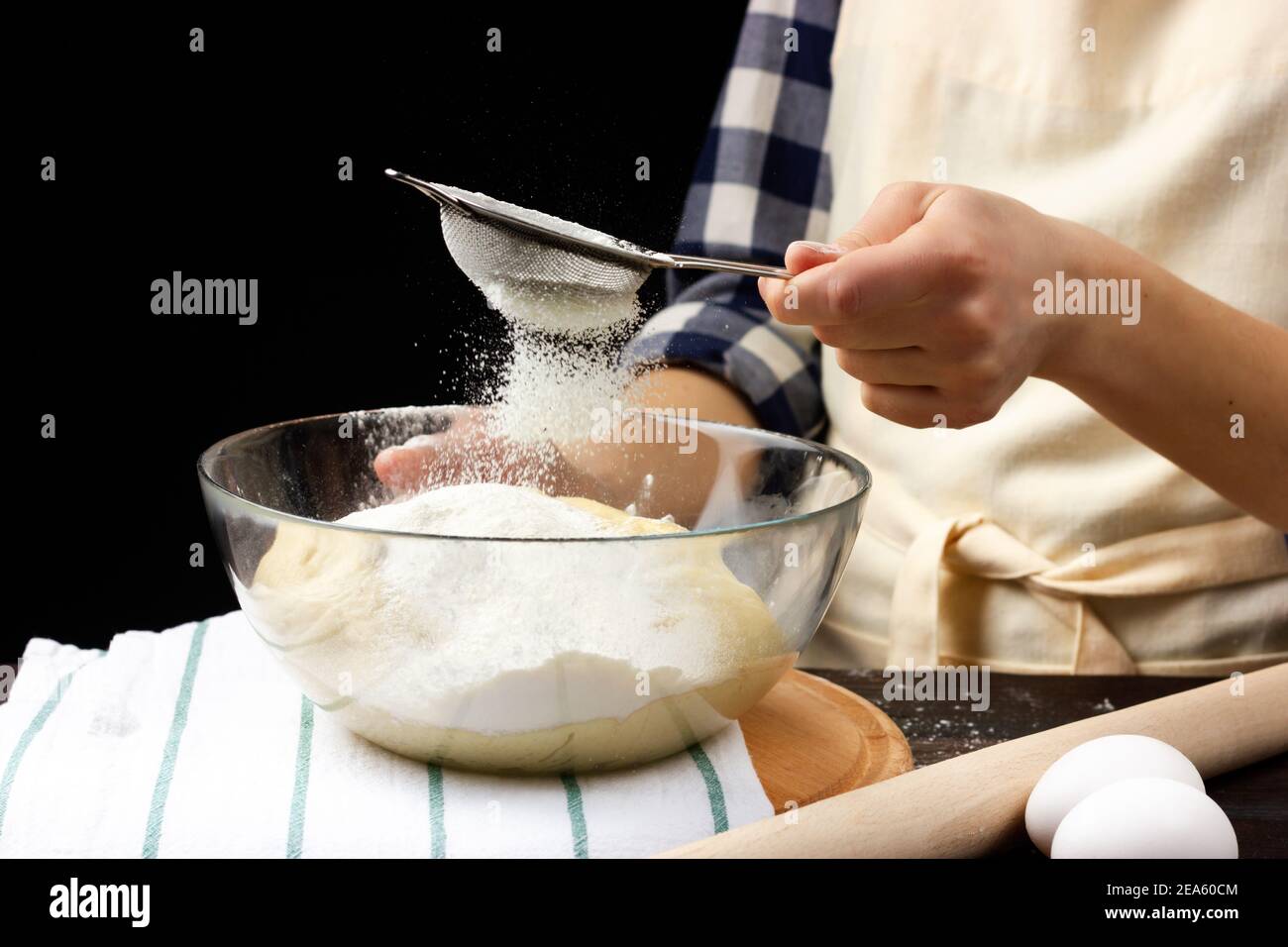 Sifting flour through a sieve. The process of making yeast dough. Woman ...