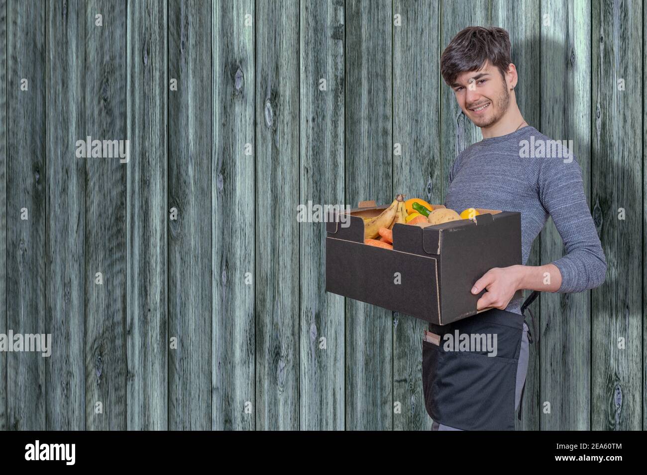 Delivery boy with fruit box in his hands delivering the order, dressed ...