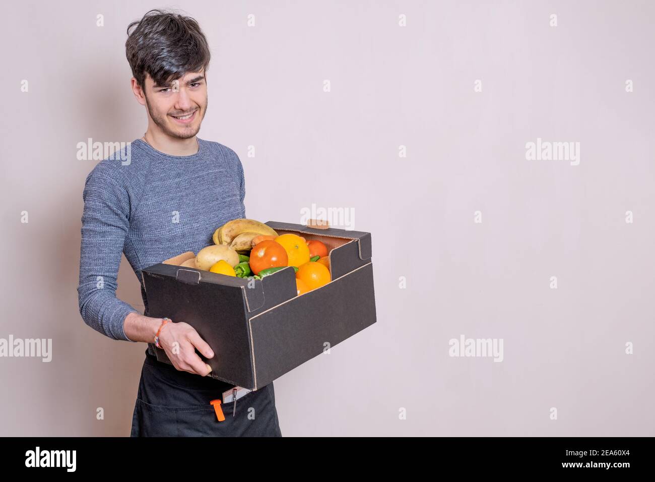 Delivery boy with fruit box in his hands delivering the order, dressed ...