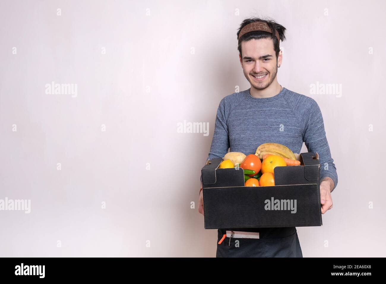 Delivery boy with fruit box in his hands delivering the order, dressed ...