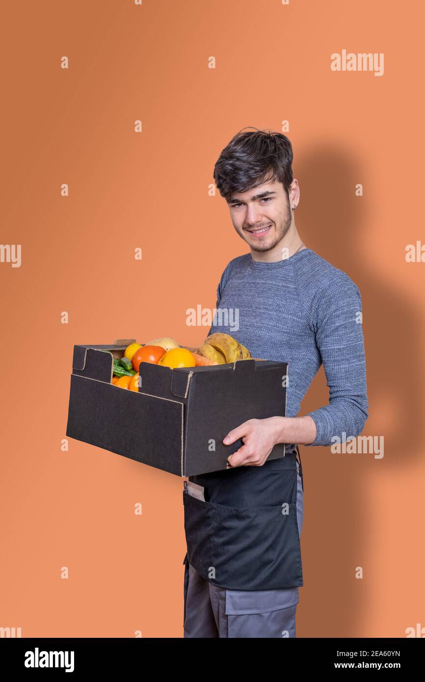 Delivery boy with fruit box in his hands delivering the order, dressed ...