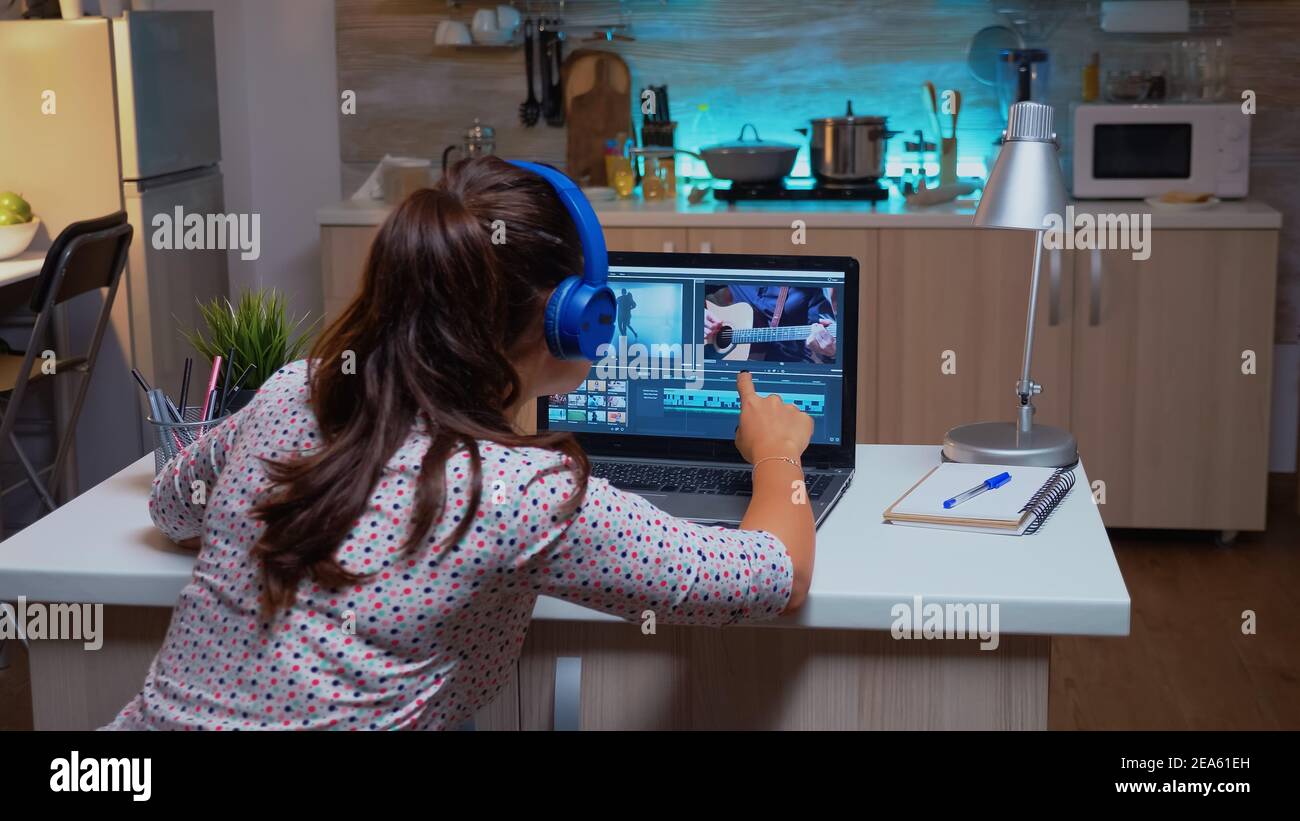 Filmmaker editing video footage during night time in home kitchen ...