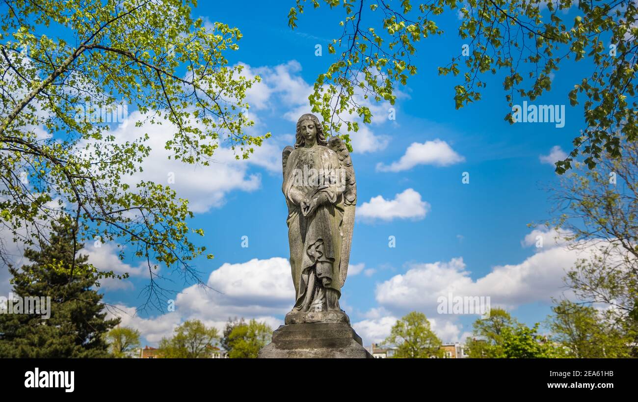 Angel statue in a cemetery with clouds and blue sky Stock Photo - Alamy