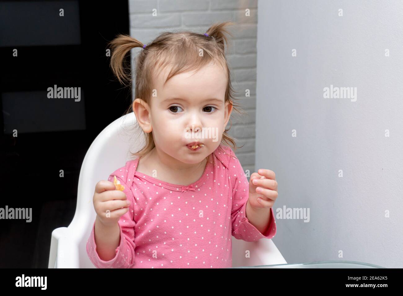 Portrait of cute little pretty caucasian kid eating with funny emotions ...