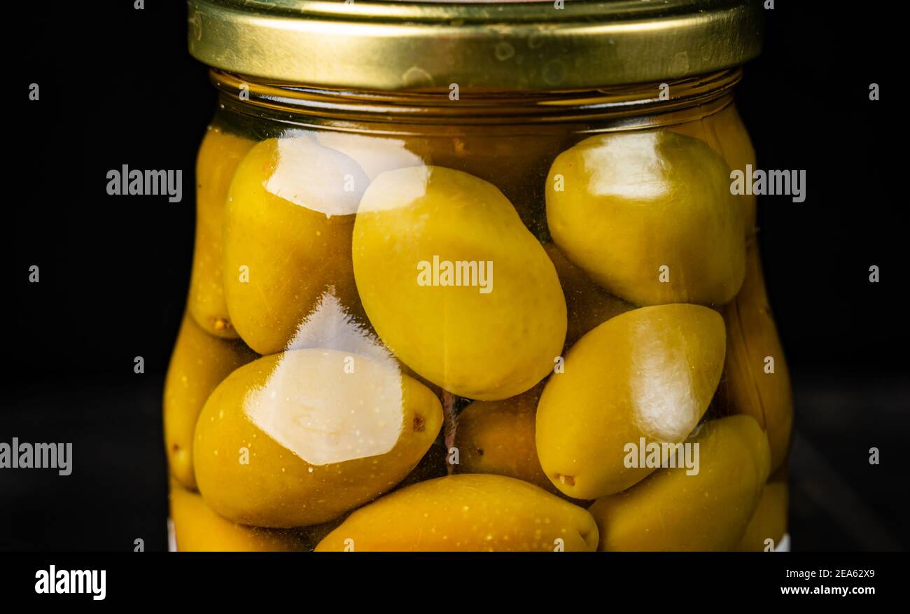Olives in a glass jar, close up. Whole green olives in brine in a ...