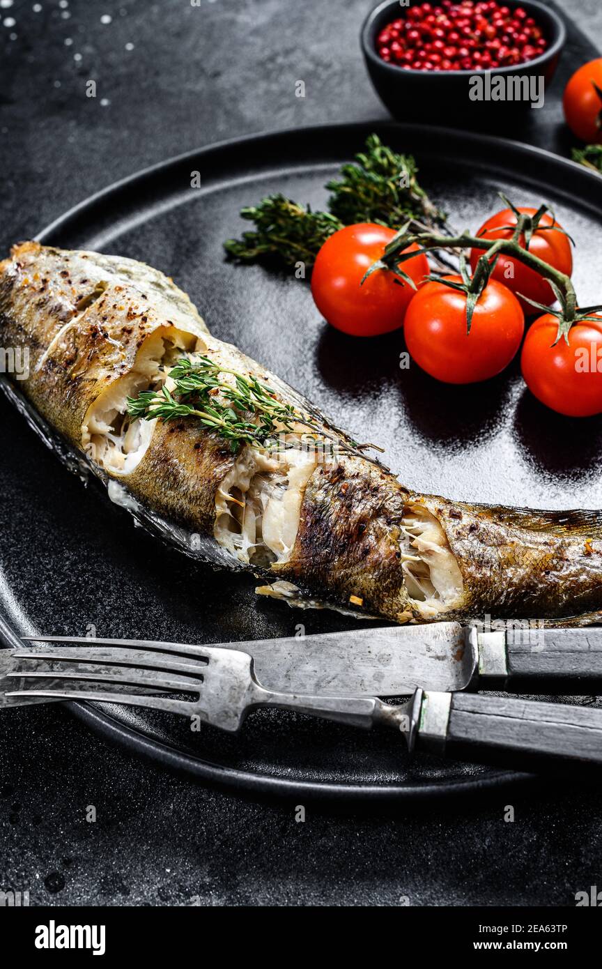Baked pollock cooked in a savory marinade. Black background. Top view ...