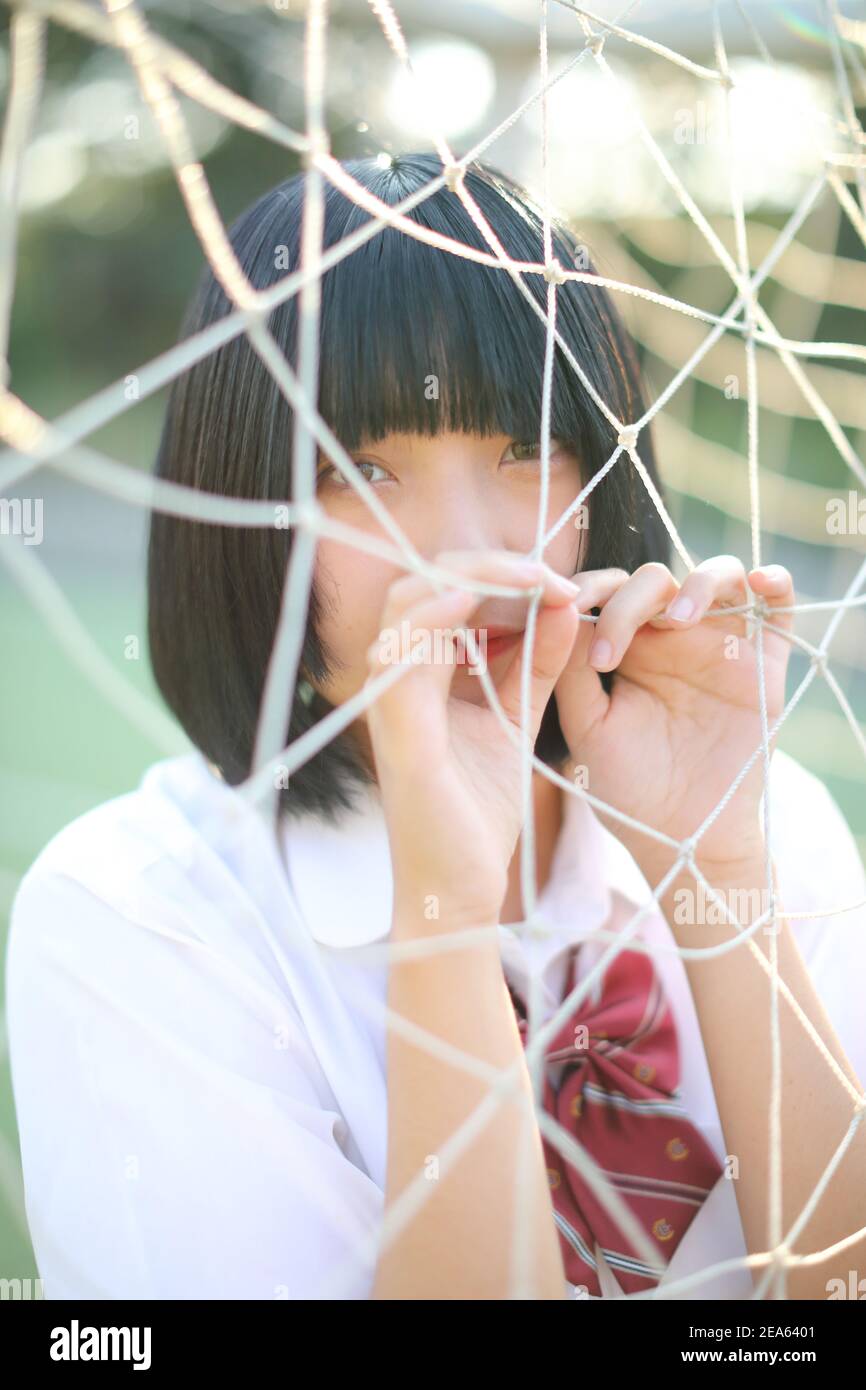 Portrait of beautiful Asian japanese high school girl uniform looking with net in green ...