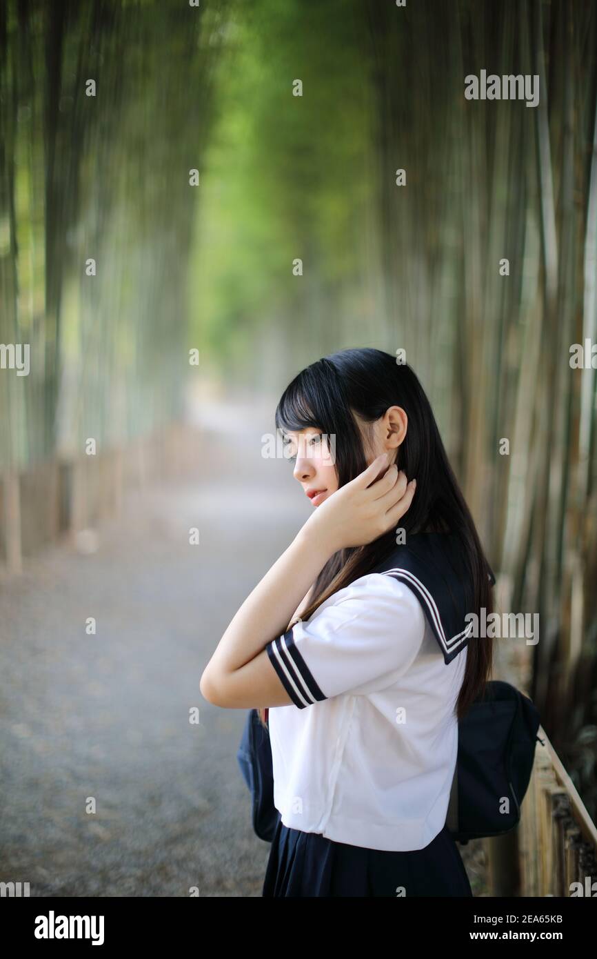 Portrait of beautiful Asian japanese high school girl uniform looking with bamboo forest ...