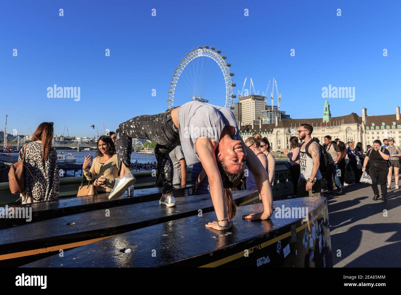 A young woman poses for a selfie with tourists watching on Westminster ...
