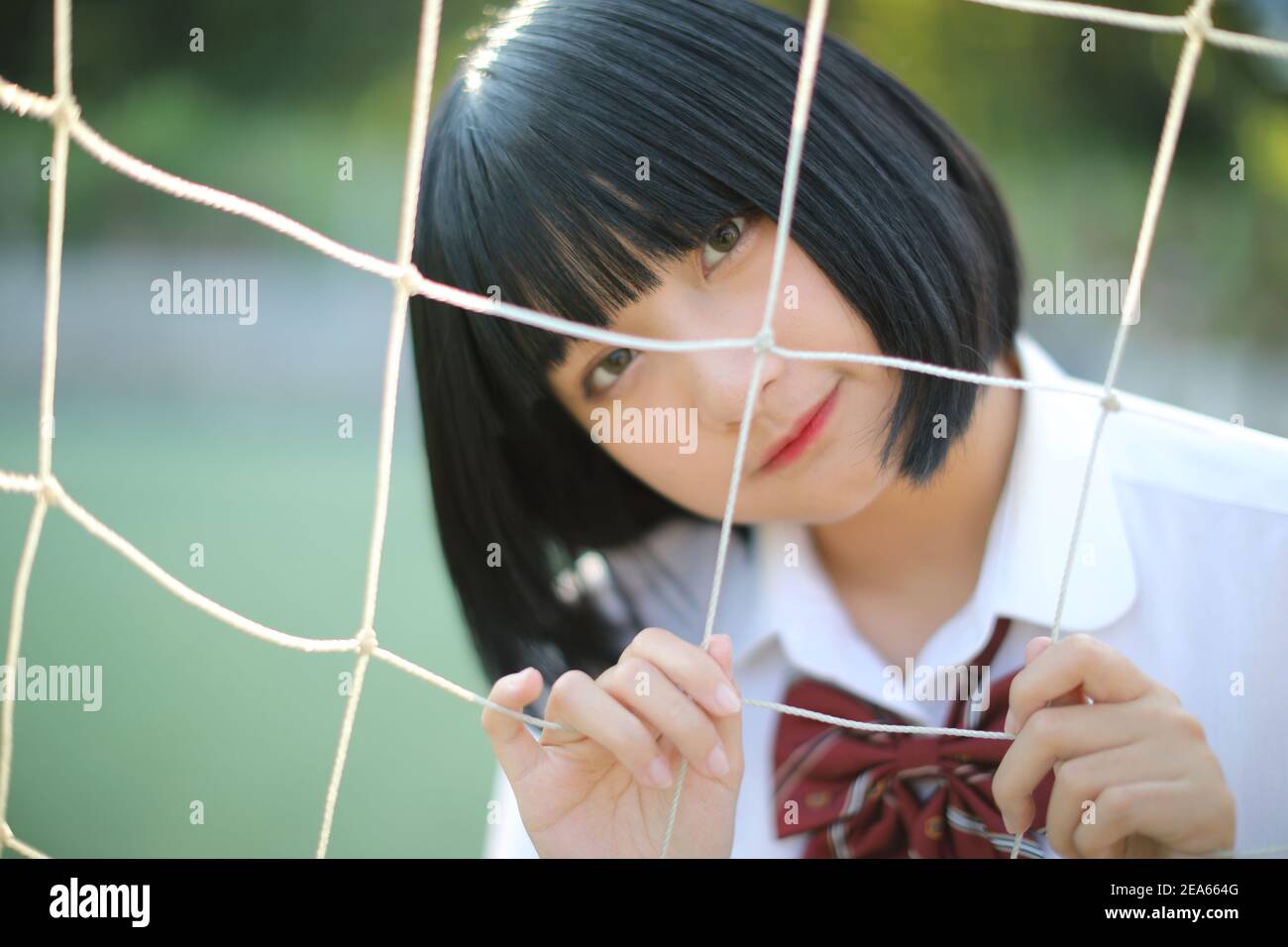 Portrait of beautiful Asian japanese high school girl uniform looking with net in green ...