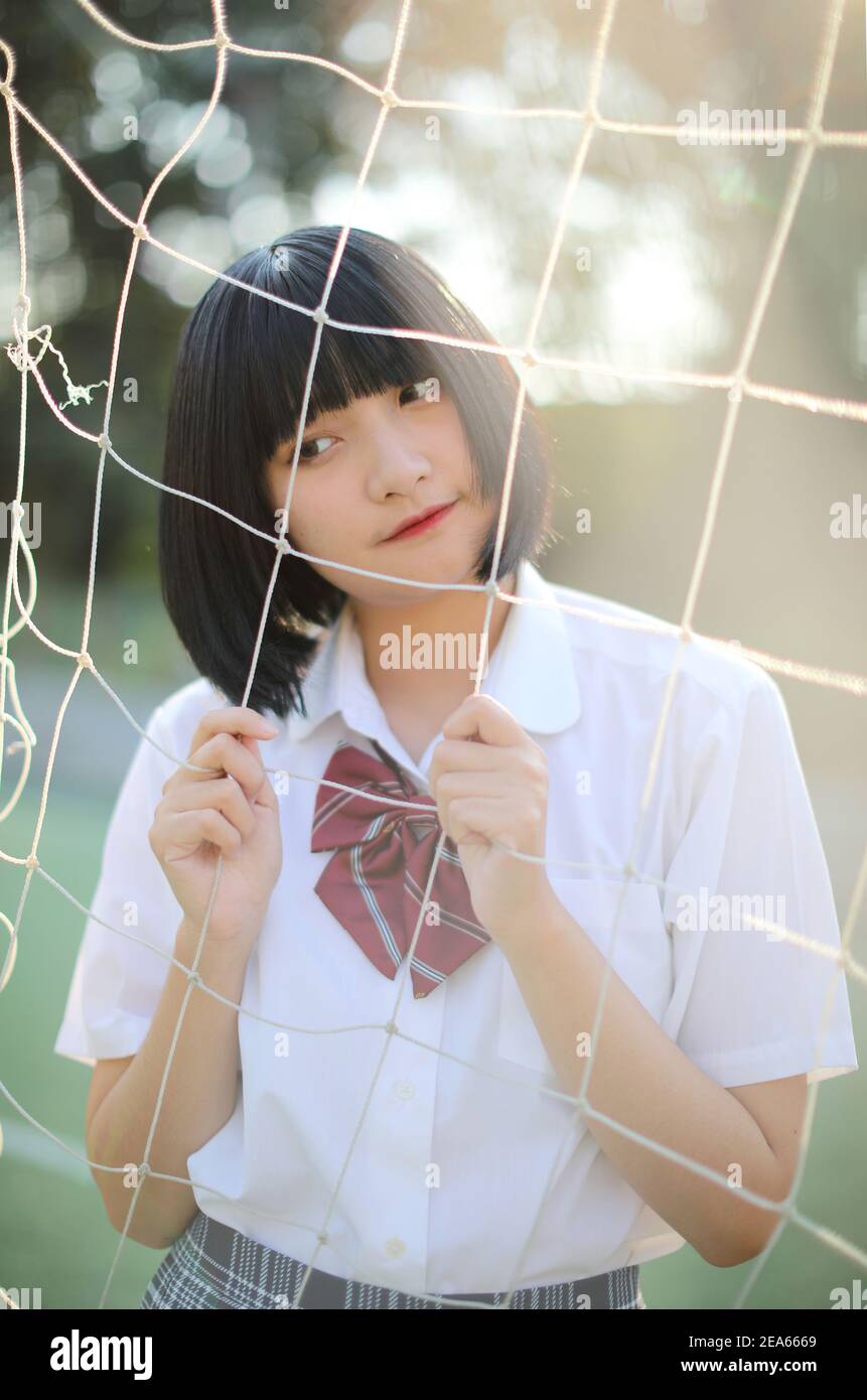 Portrait of beautiful Asian japanese high school girl uniform looking with net in green ...