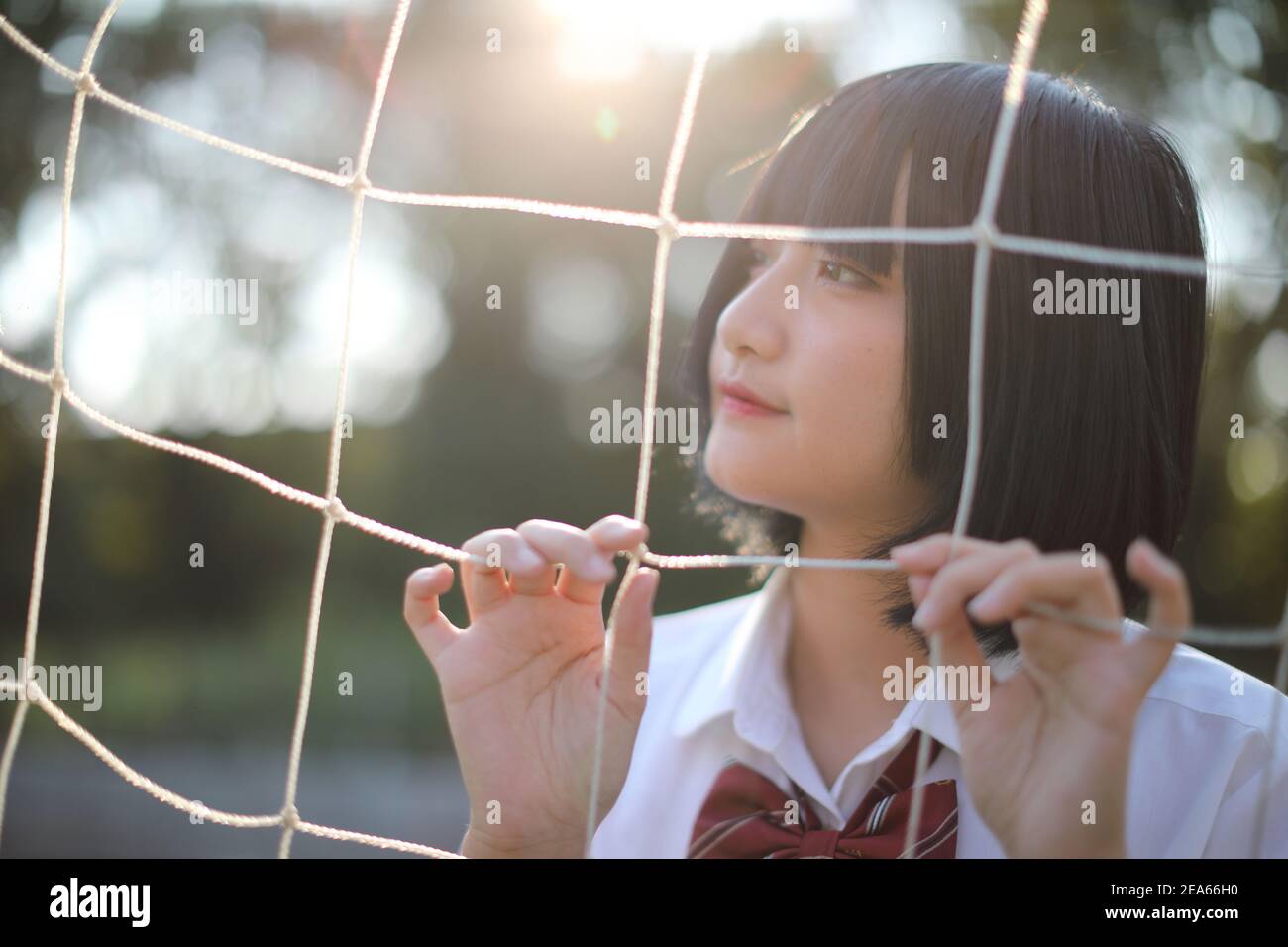 Portrait of beautiful Asian japanese high school girl uniform looking with net in green ...