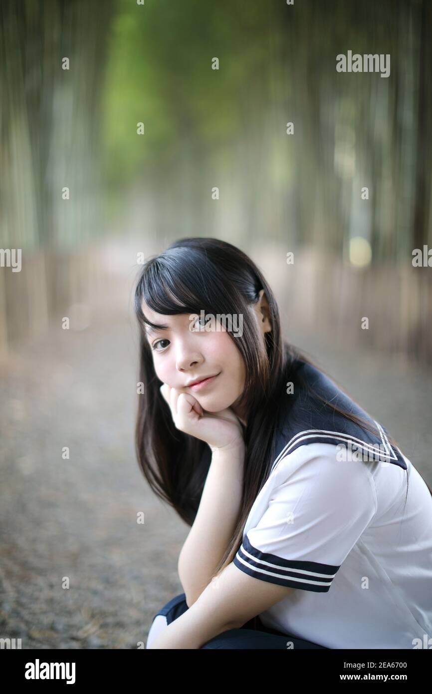Portrait of beautiful Asian japanese high school girl uniform looking with bamboo forest ...
